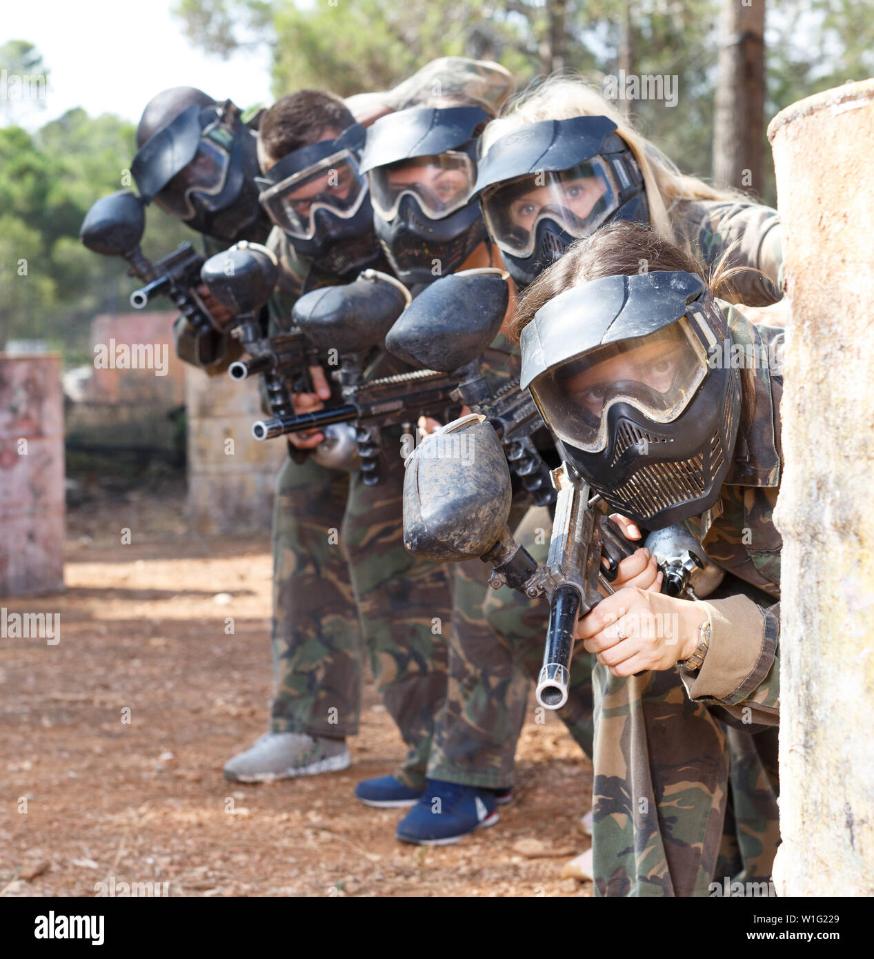 Portrait of team of adult people playing on paintball battlefield ...