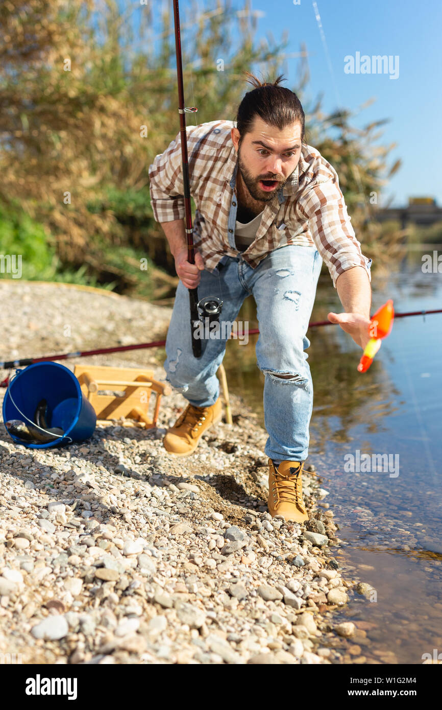 Happy fisherman pulls fish out of the river Stock Photo - Alamy