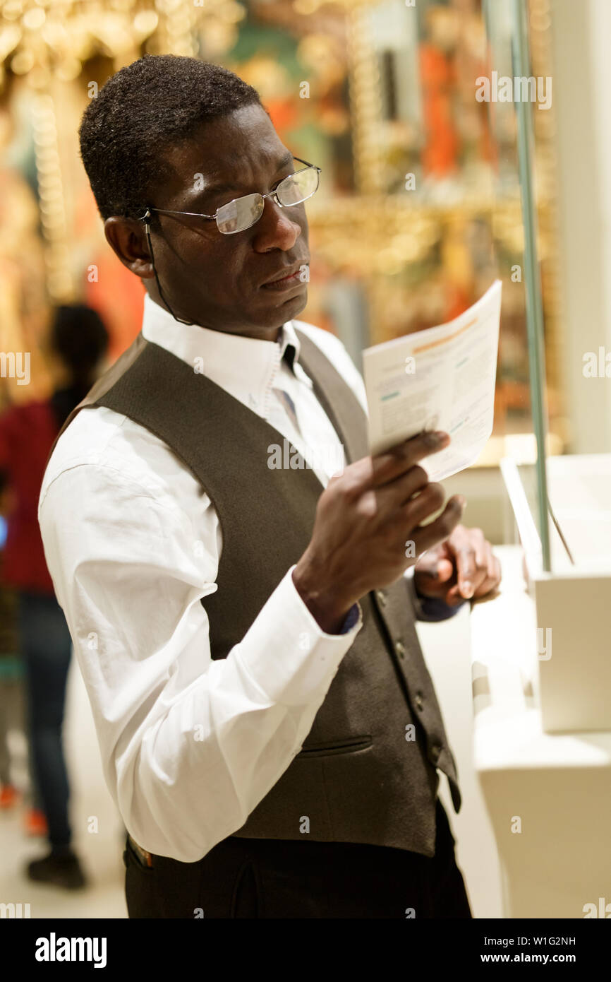 Mature african man reading brochure about exhibits on exposition of ...