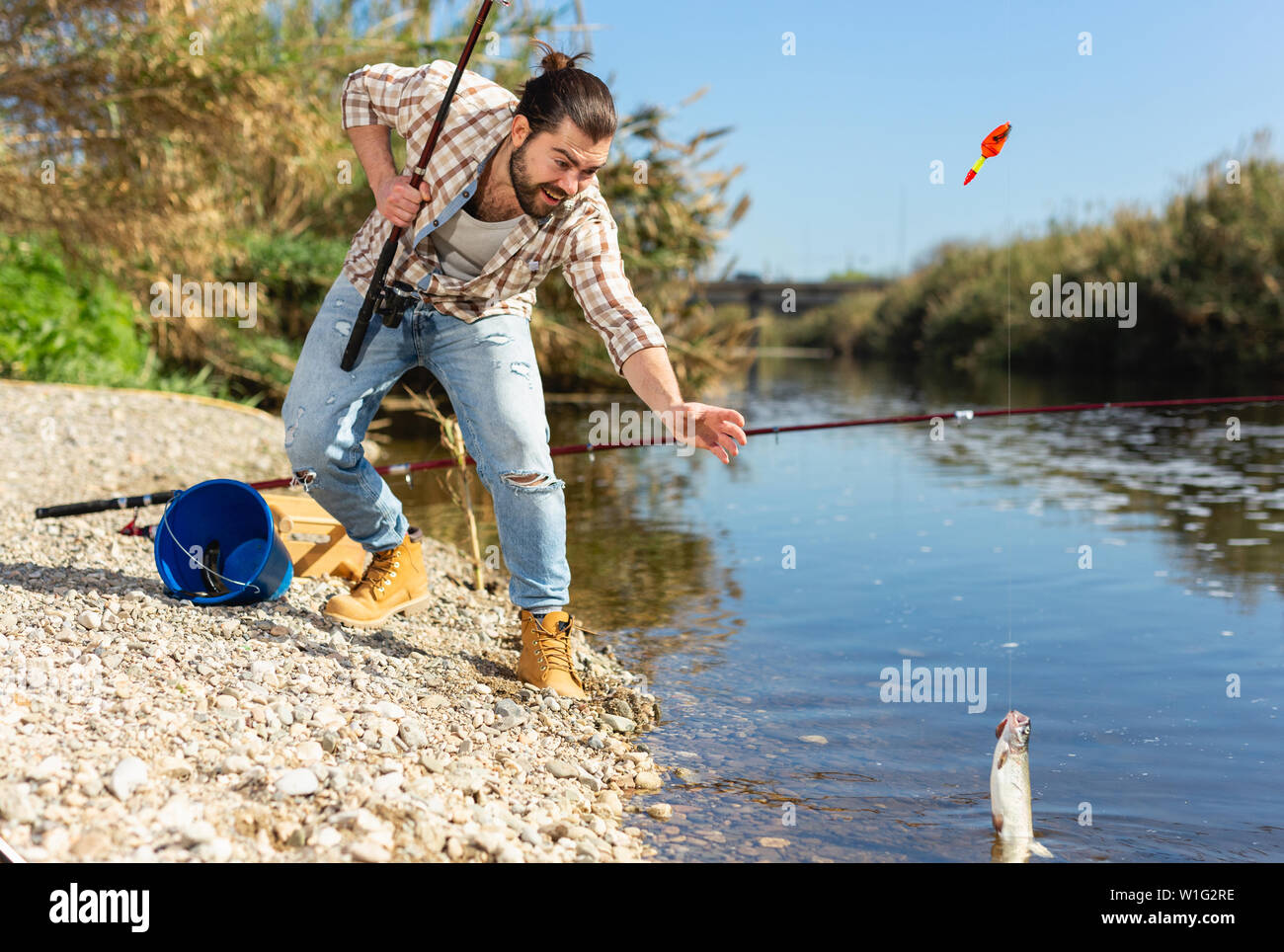 Happy fisherman pulls fish out of the river Stock Photo - Alamy