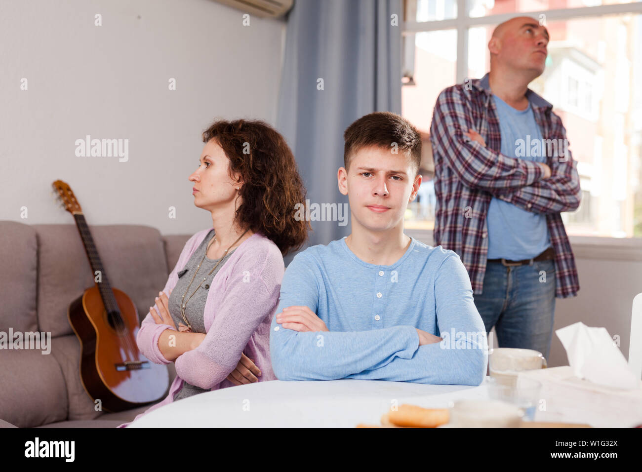 Portrait of upset teenage boy and his frustrated parents in home ...