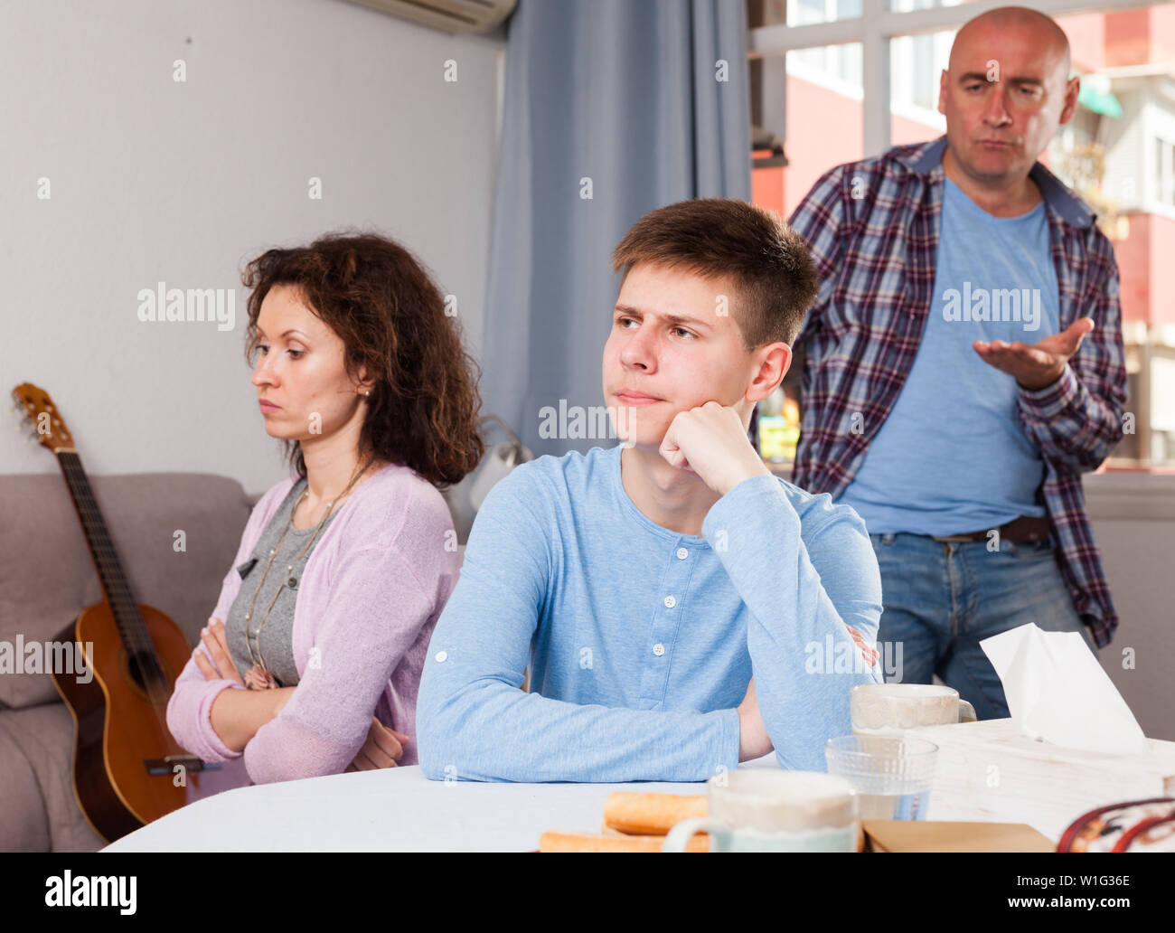 Portrait of upset teenage boy and his frustrated parents in home ...