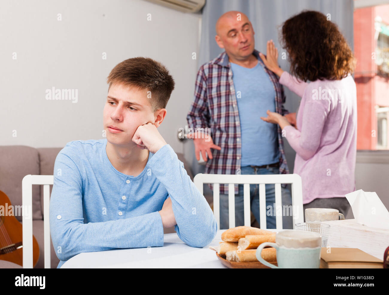 Portrait of desperate teenager boy during parents arguing in home ...