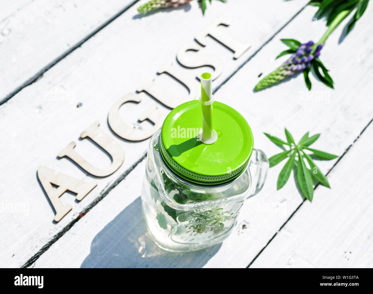Jar of lemonade and the word August on a white wooden rustic background ...