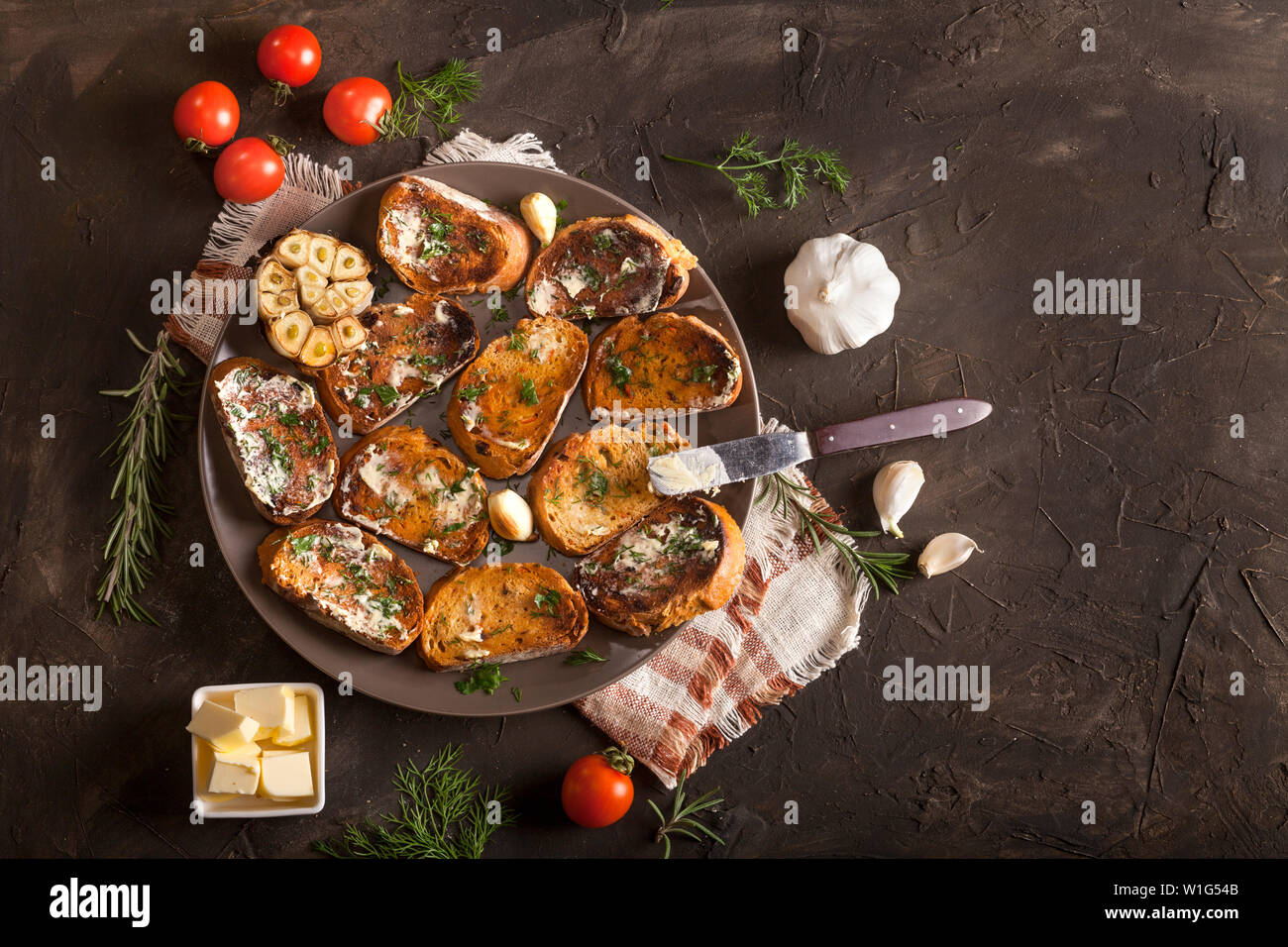 Sliced traditional toast bread with butter, garlic and herbs on a brown ...