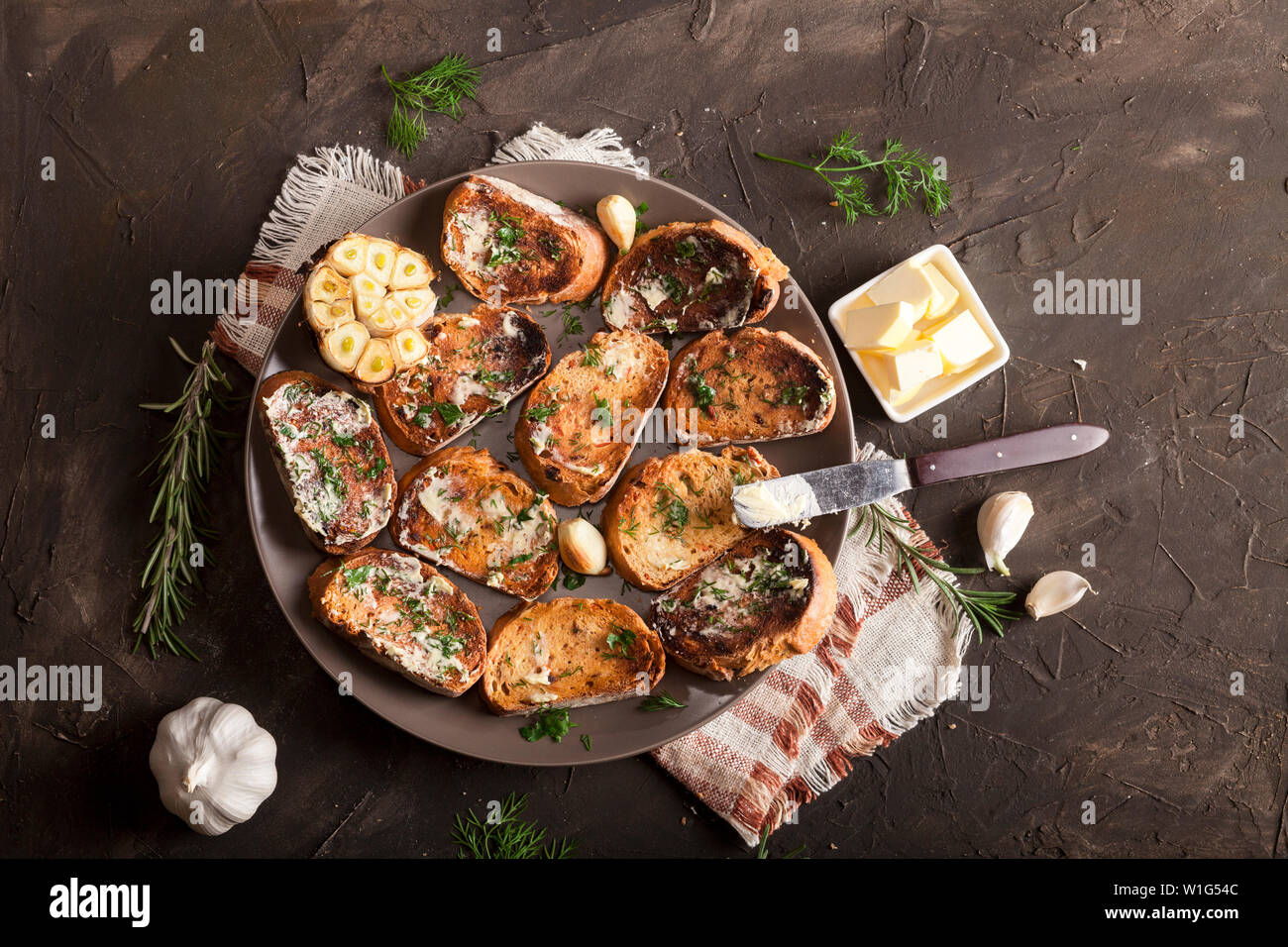 Sliced traditional toast bread with butter, garlic and herbs on a brown ...