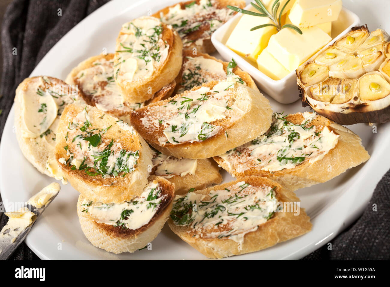 Sliced traditional toast bread with butter, garlic and herbs on a white ...
