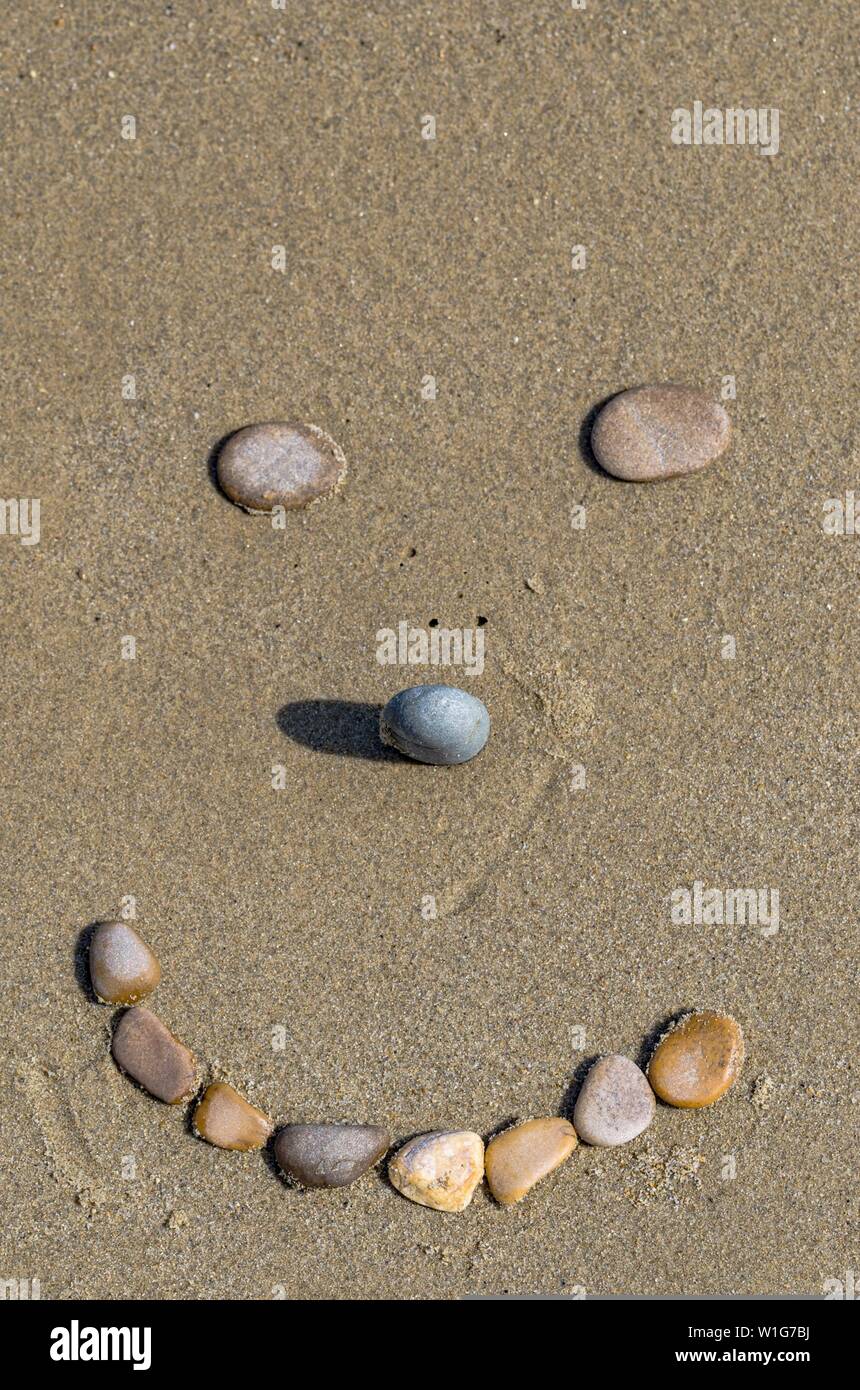Stones forming a smiling face on the sand Stock Photo - Alamy