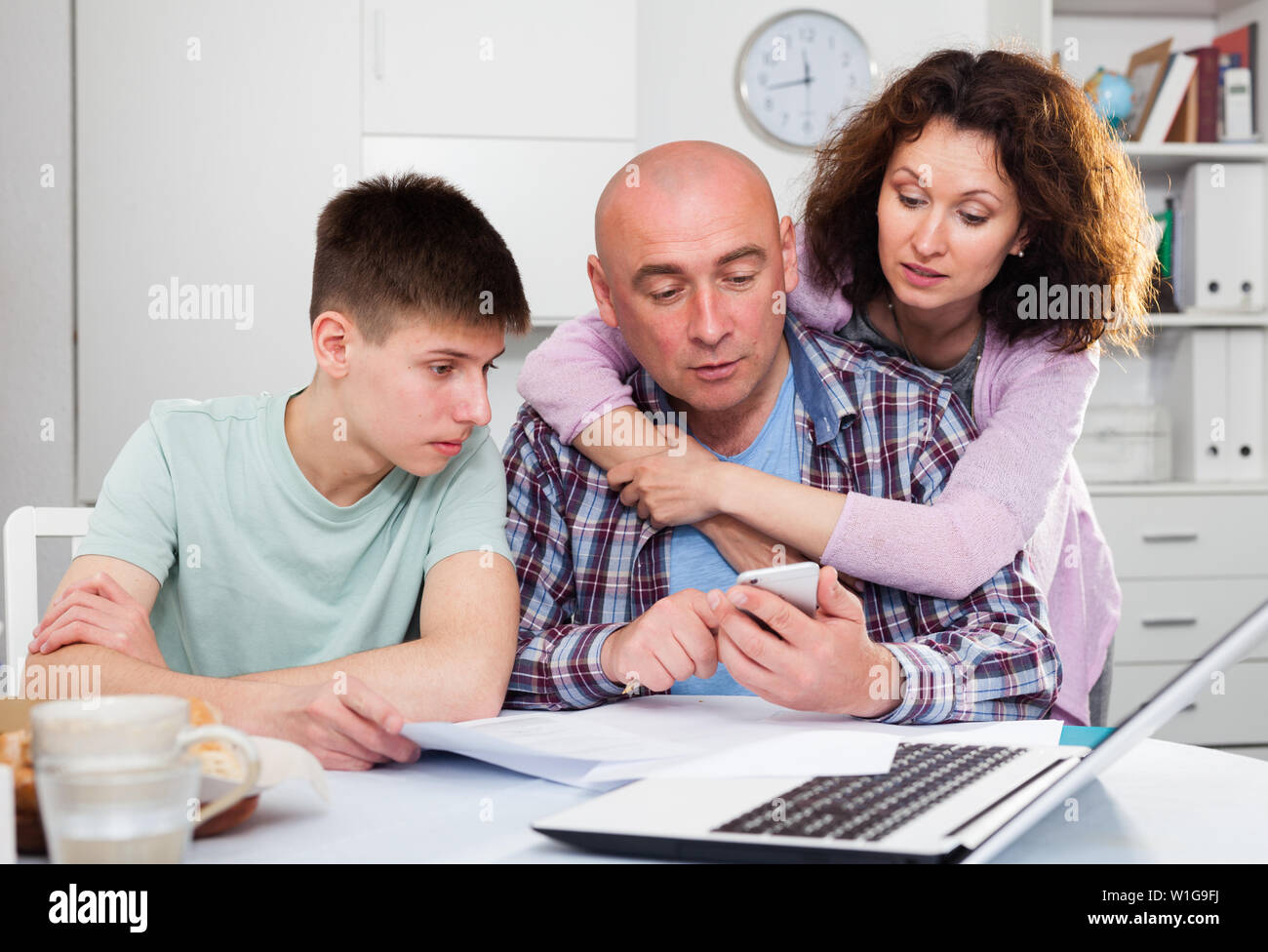 Portrait of family with teenage son working with papers at home Stock ...