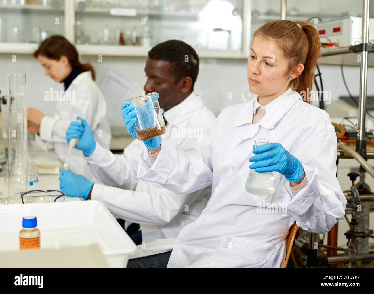 Focused women lab technicians in glasses working with reagents and test ...