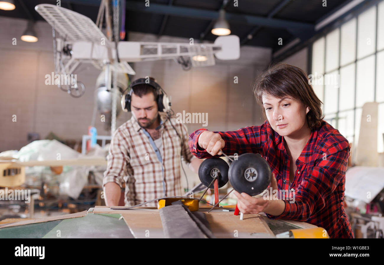 Female aircraft enthusiast engaged in creating plane models in workshop ...