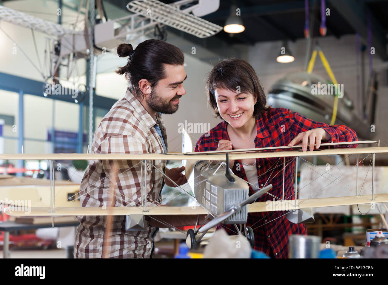 Portrait of casual female and male hobbyists with plane models created ...