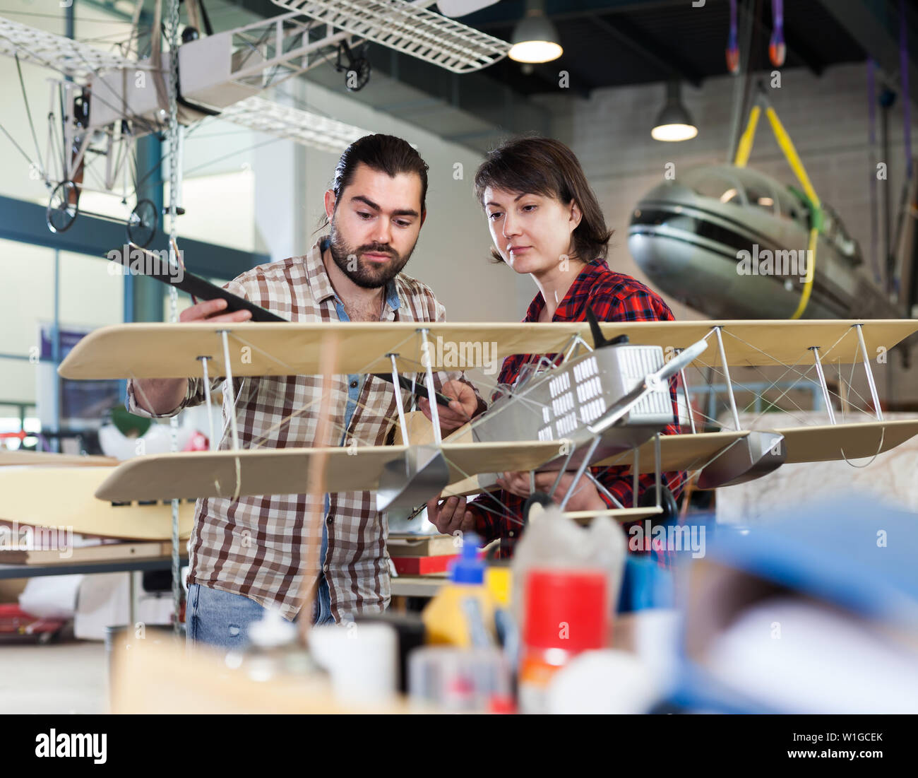 Woman and man hobbyists engaged in modeling plane models in aircraft ...