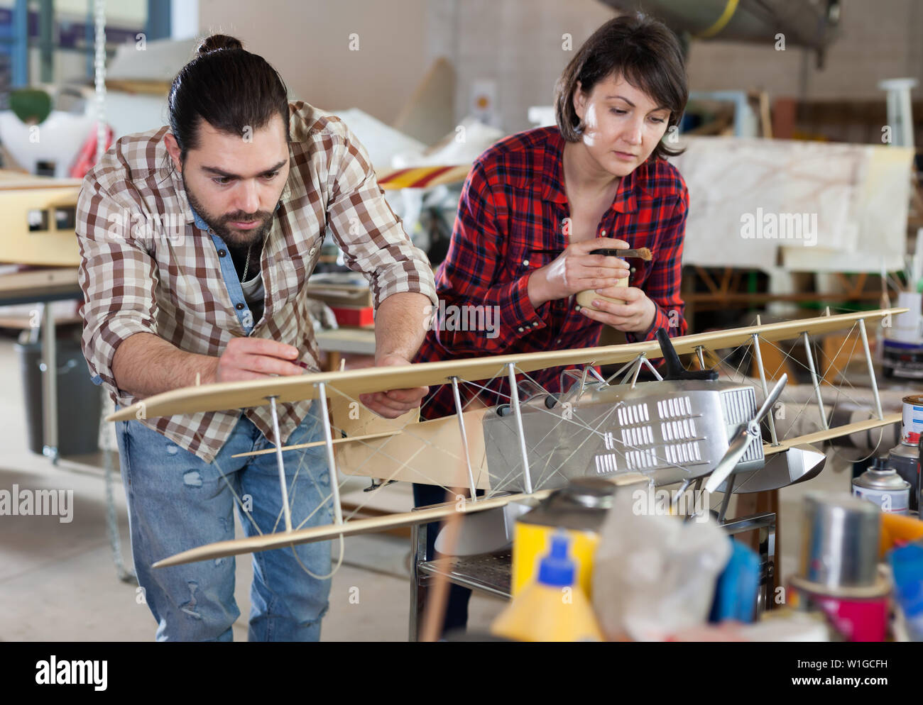 Portrait of happy female and male hobbyists with plane models created ...
