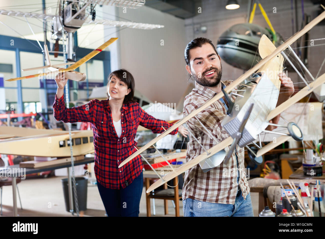 Positive smiling team of aircraft enthusiasts holding sports airplane ...