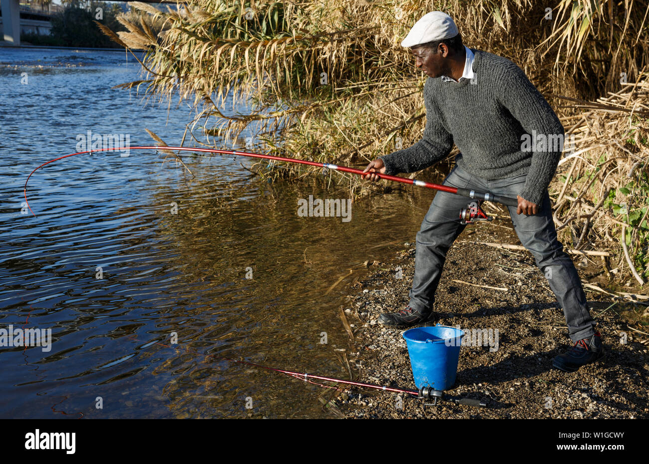 Portrait of afro fisherman standing near river and pulling fish Stock ...