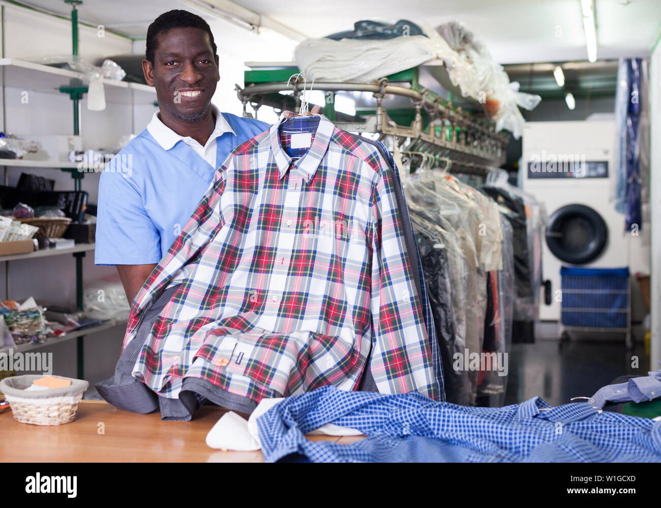 Cheerful African American man worker of dry cleaner standing at ...