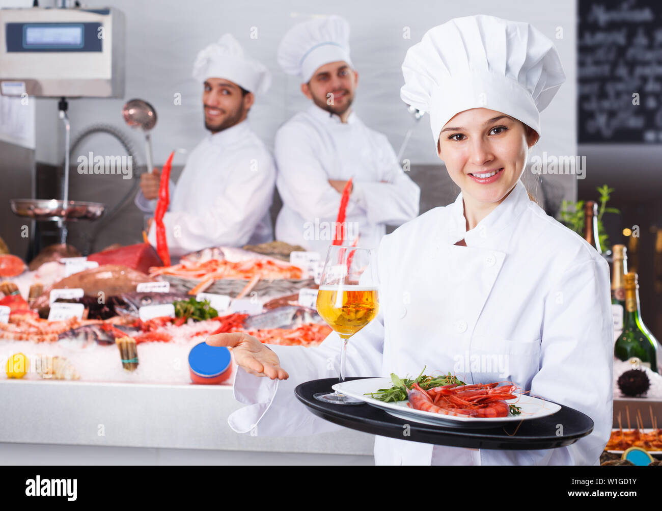 smiling woman chef standing with serving tray in fish restaurant Stock ...