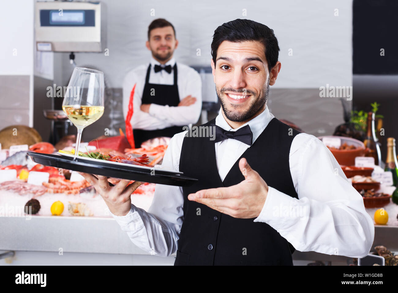 Handsome bearded waiter standing with serving tray in seafood ...