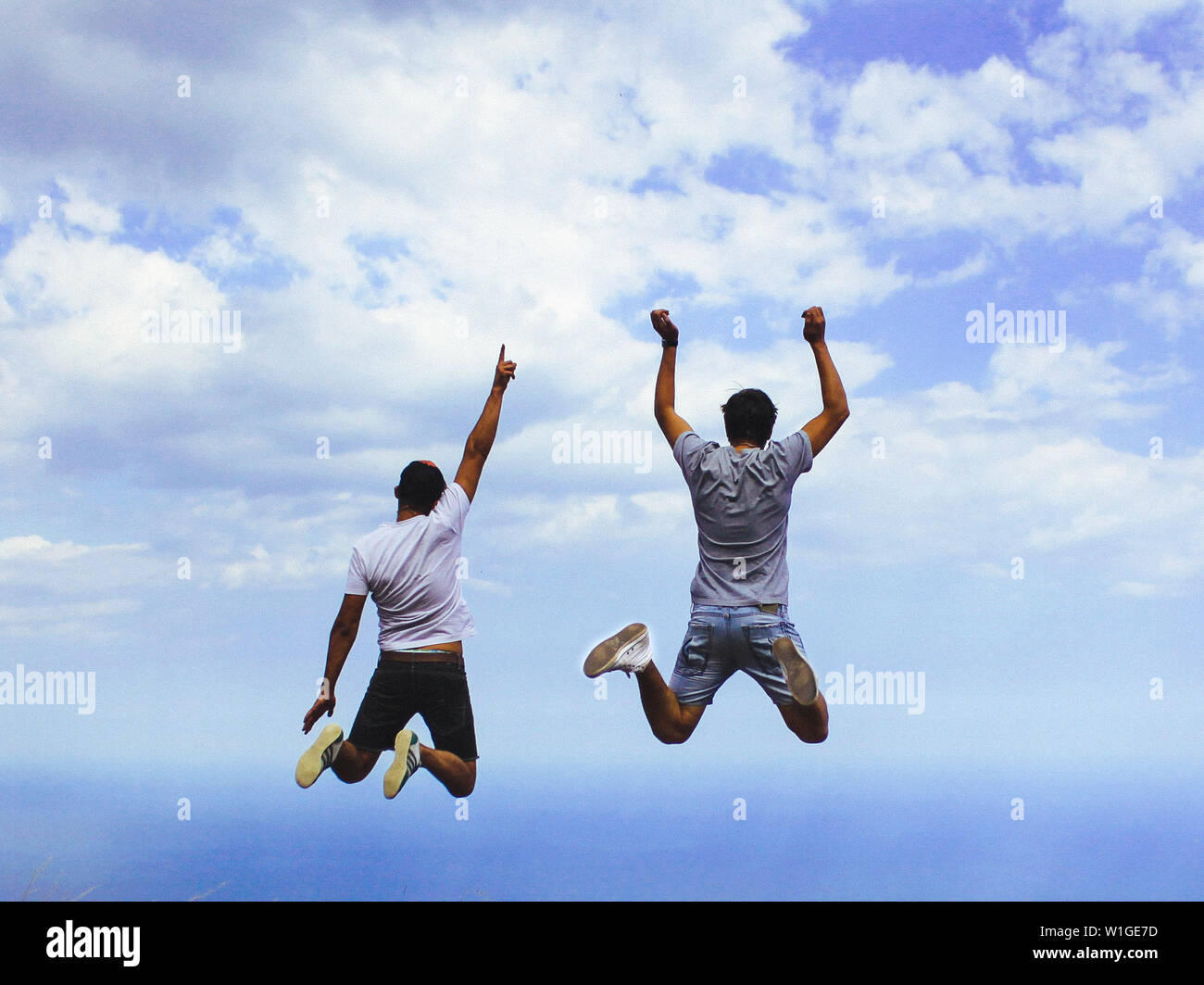 Happy two young man jump on sky Stock Photo - Alamy