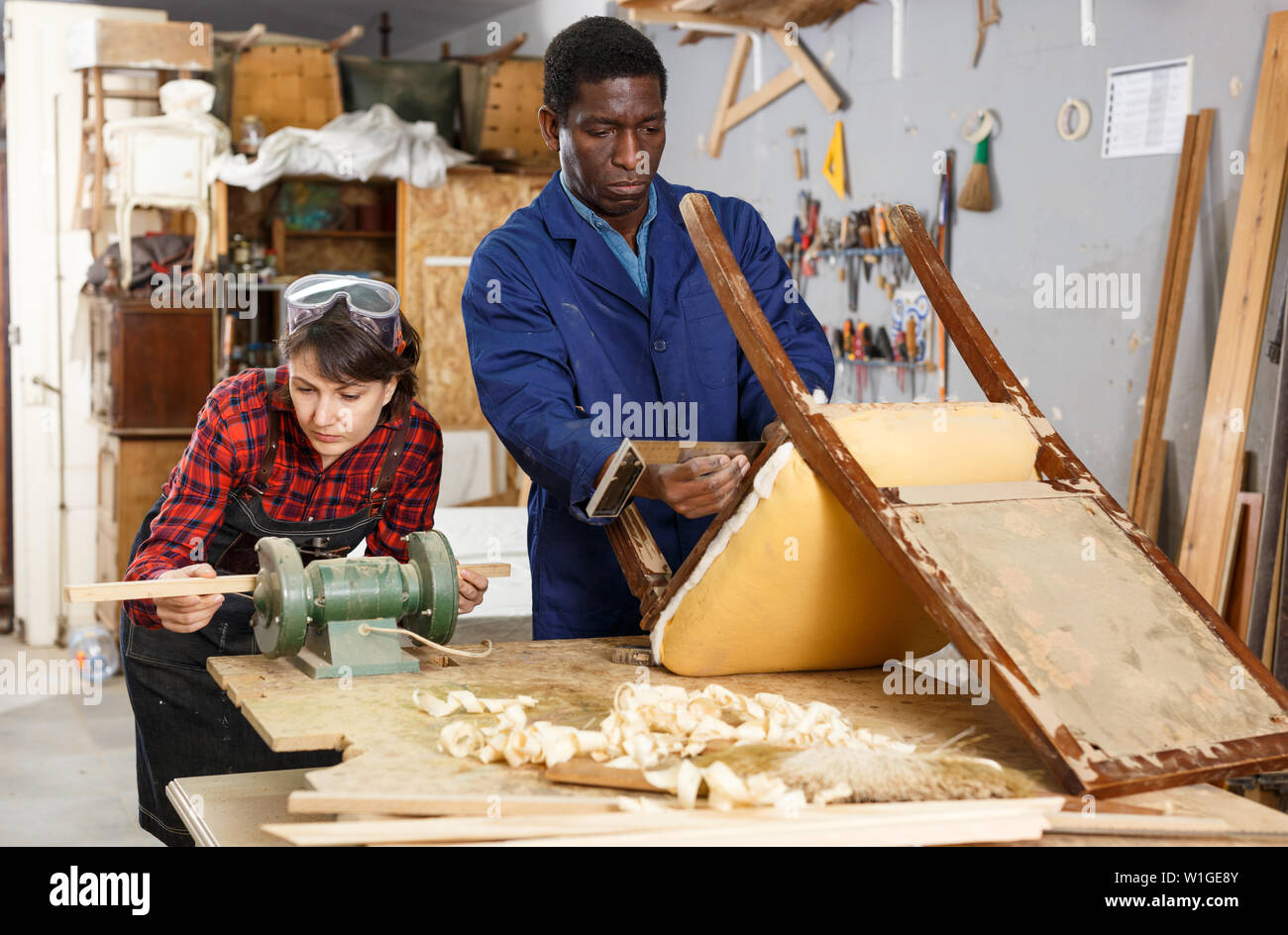 Woman and man carpenters using tools for restoration wooden chair in ...