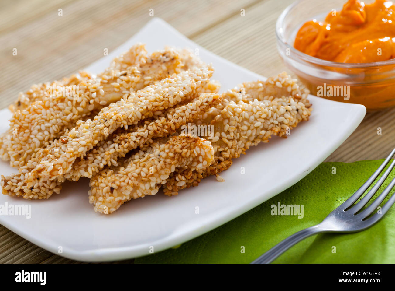 Fried chicken fingers from fillet in sesame served at plate on table ...