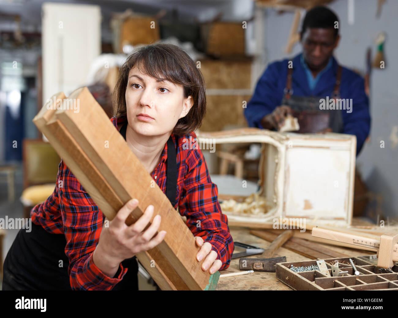 Woman carpenter using tools for creating wooden furniture in studio ...