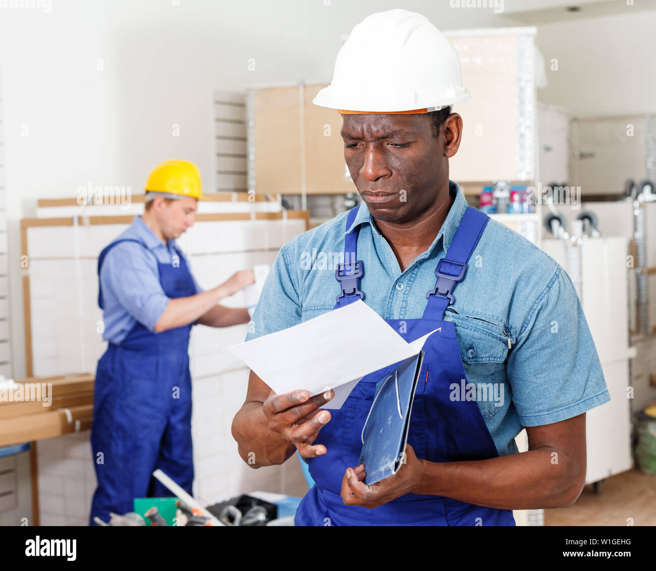 Focused African-American contractor reading building documents at ...