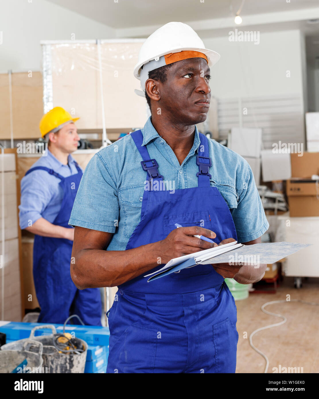 Confident African-American builder examining room and planning ...
