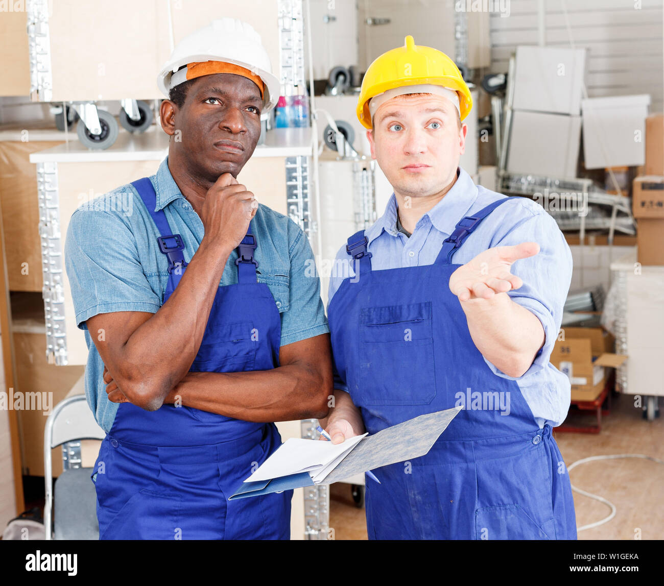 Confident builders discussing while examining room and planning ...