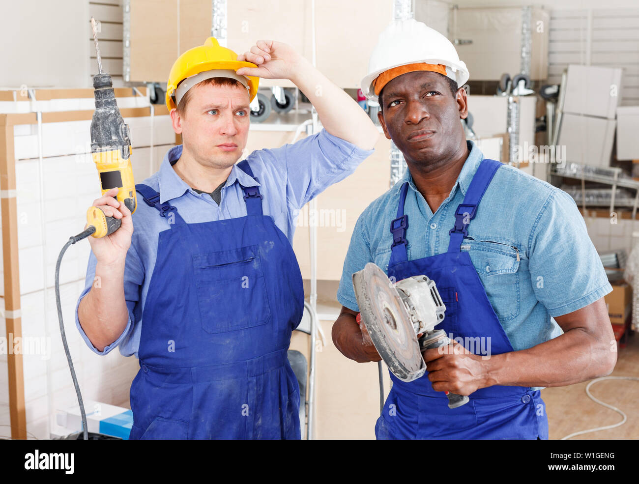 Confident male contractors working with handheld power tools in ...