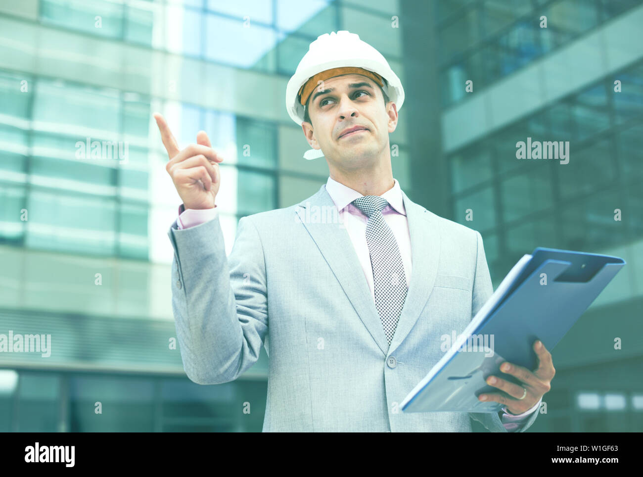 Portrait of manager of plant giving instructions and pointing with his ...