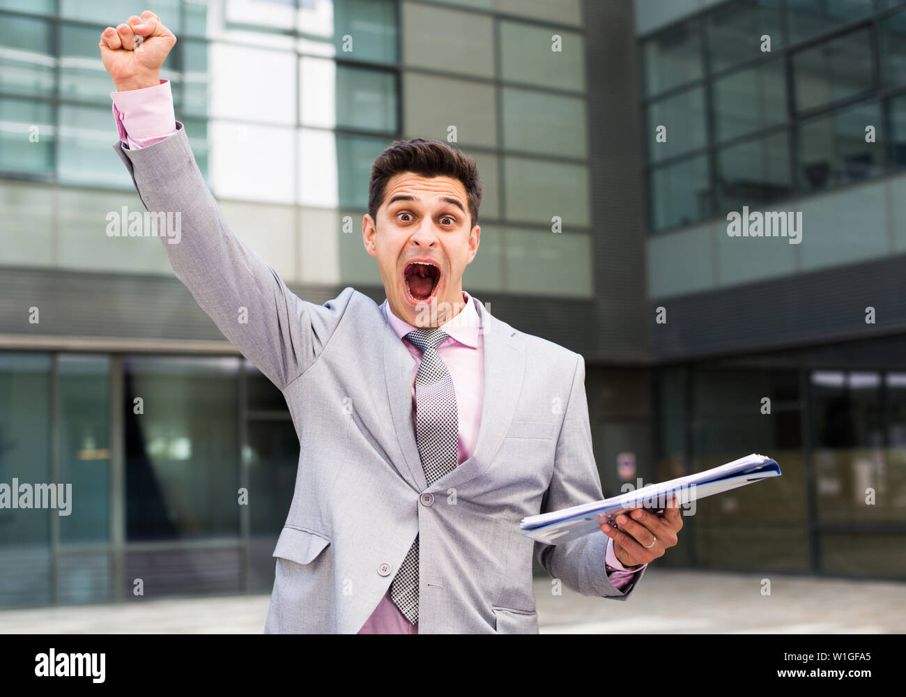 Successful businessman with arm up expressing satisfaction outdoor ...