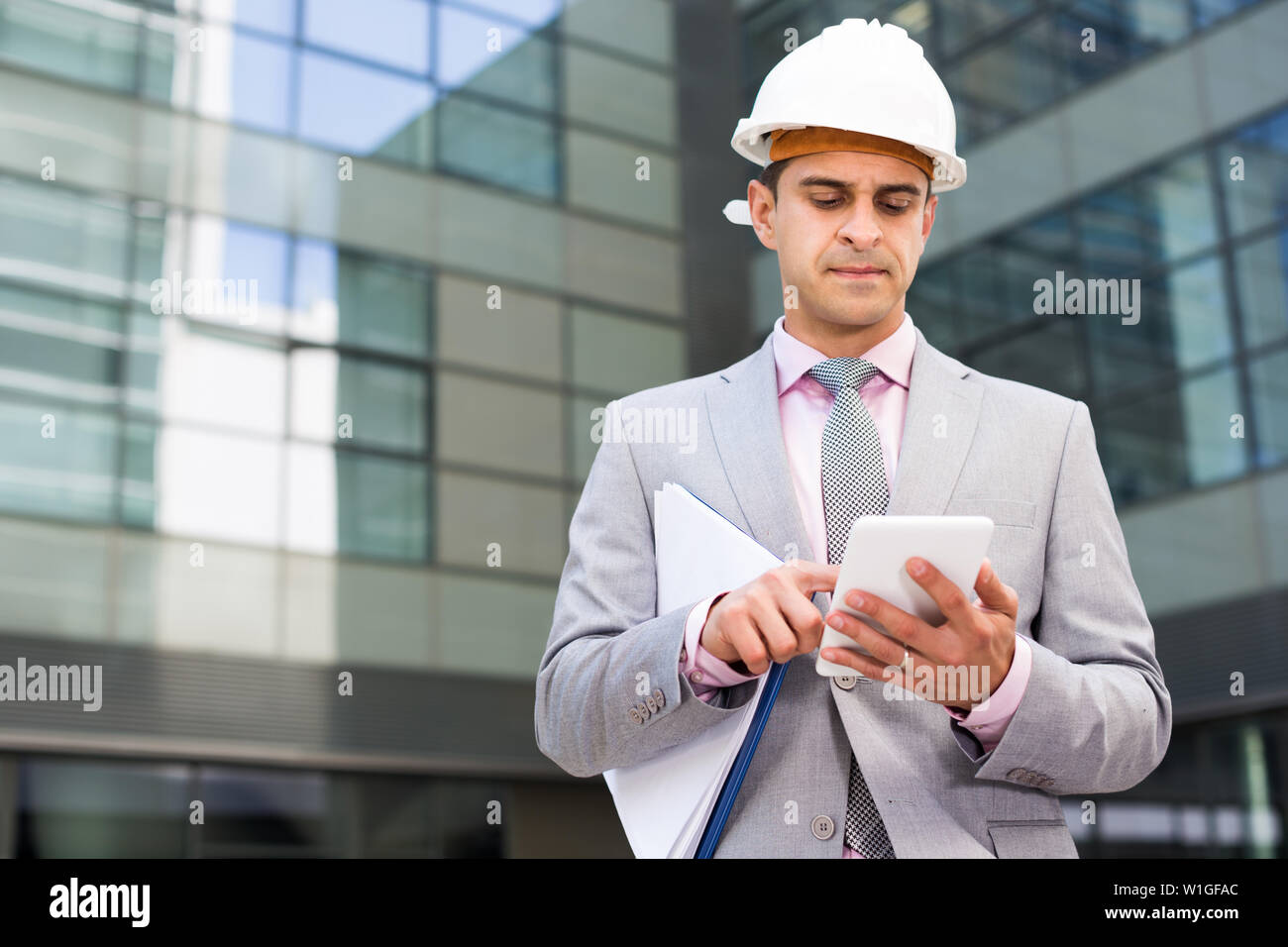Confident young businessman standing on factory background and using cell phone Stock Photo - Alamy