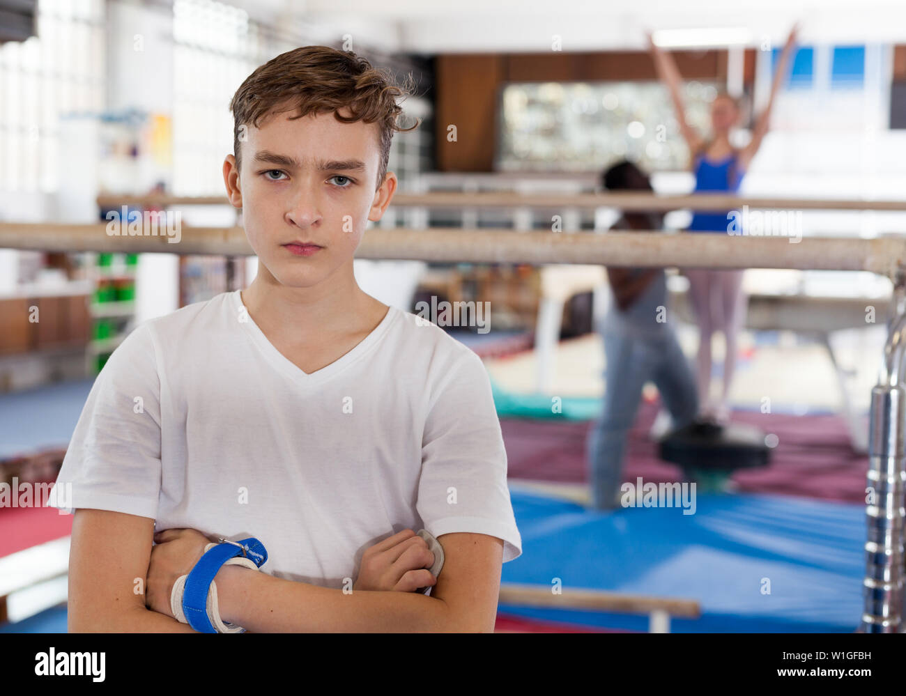 Unhappy tired teenage boy in sportswear standing near parallel bars at ...