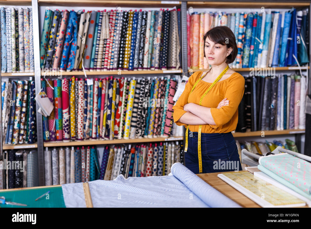 Successful female owner of fabric store standing on background with ...