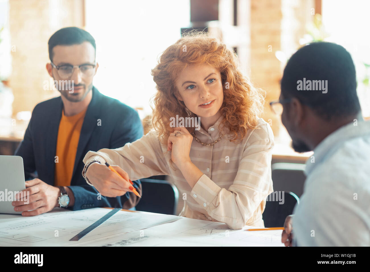 Talking to boss. Beautiful red-haired interior designer talking to her ...