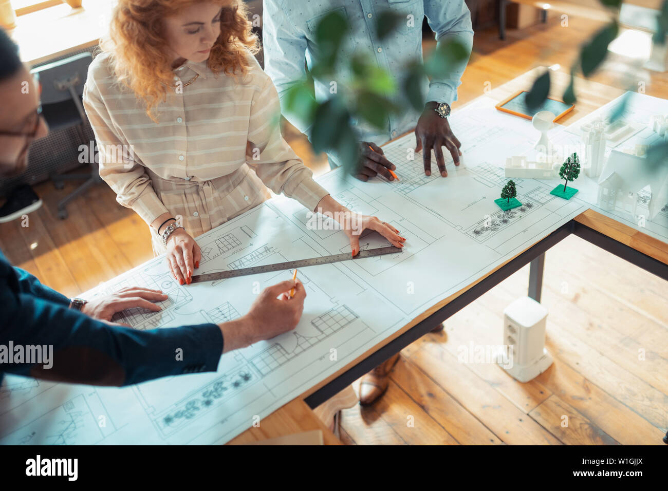Woman making sketches. Curly red-haired experienced woman making ...