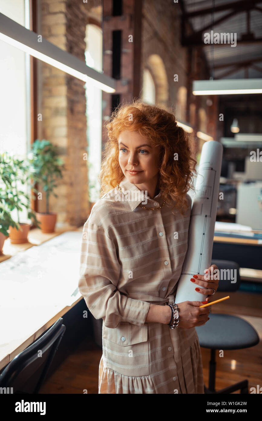 Designer holding sketches. Red-haired beautiful interior designer ...