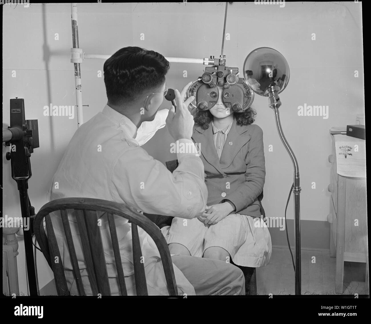 Minidoka Relocation Center. Doctor Geo. Tani. Doctor examining eyes of ...
