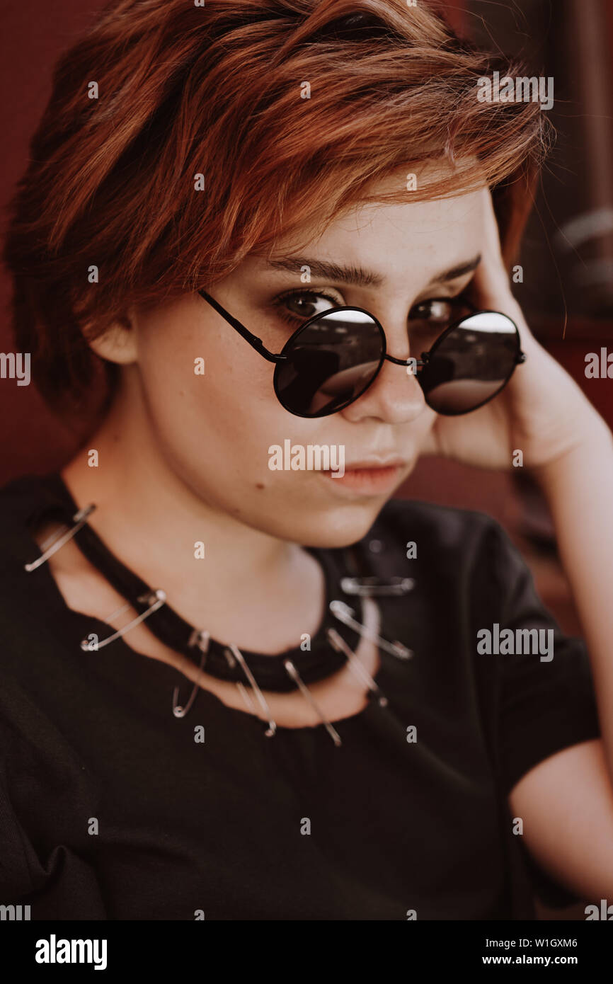 Portrait of attractive cheeky woman with short red hair in sunglasses ...