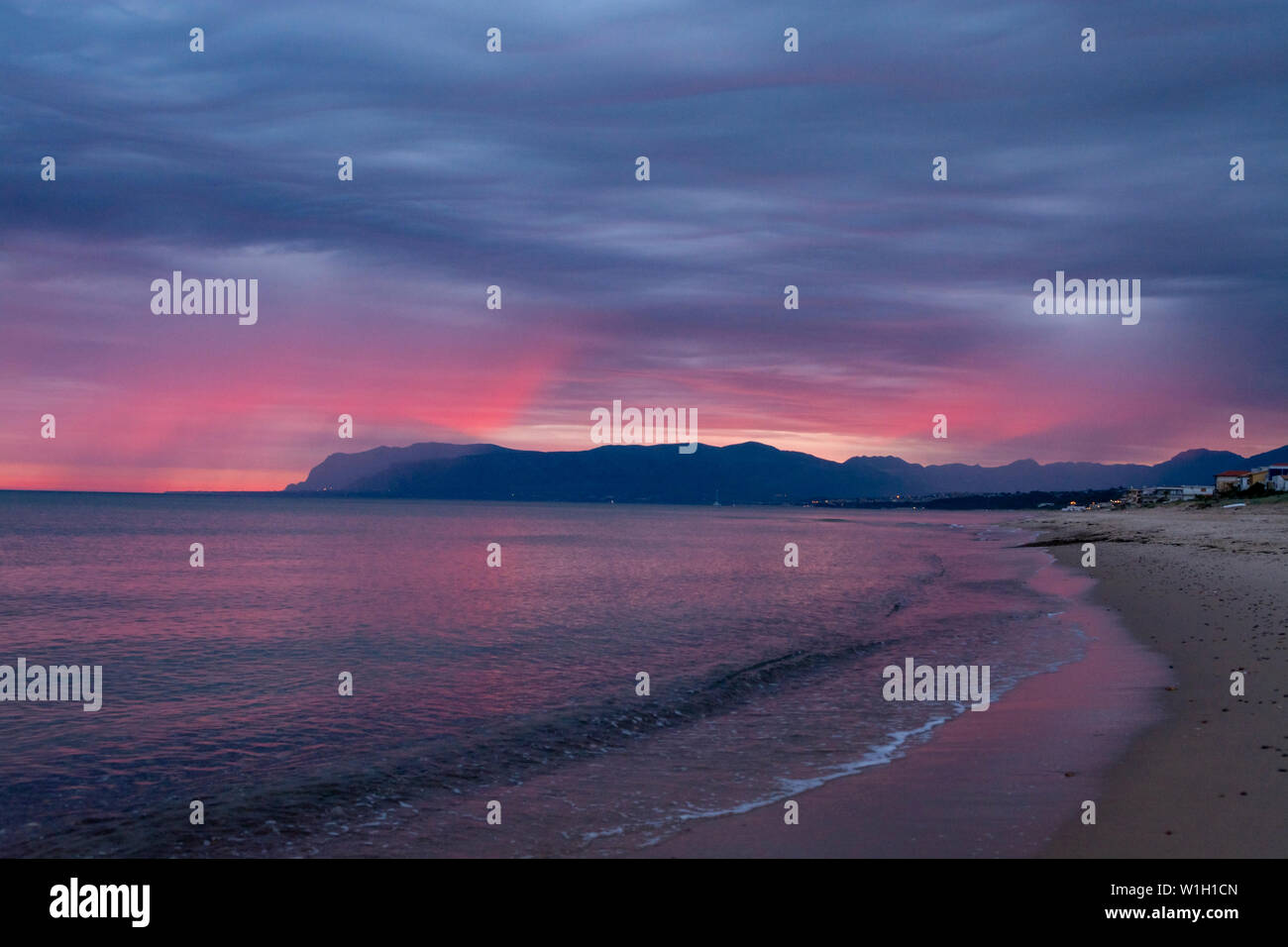 Scenic pink-red sunrise over coastline with sandy beach and clear sea ...