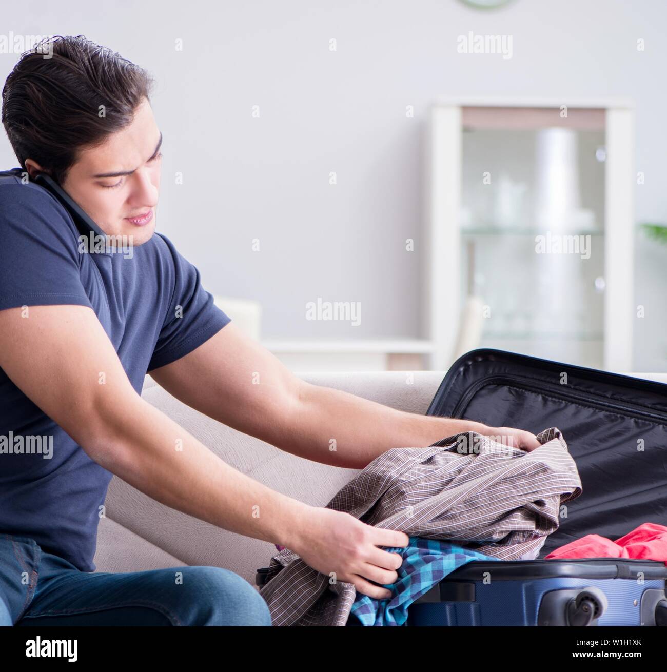 Young man preparing packing for summer vacation Stock Photo - Alamy