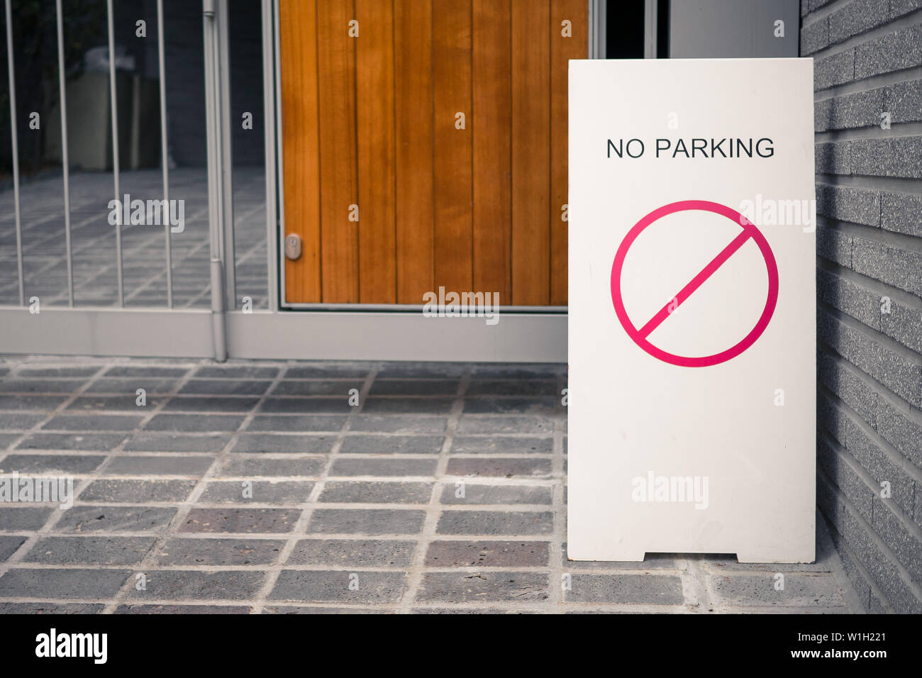 A rectangular vertical sign "no parking" is on the asphalt in front of ...