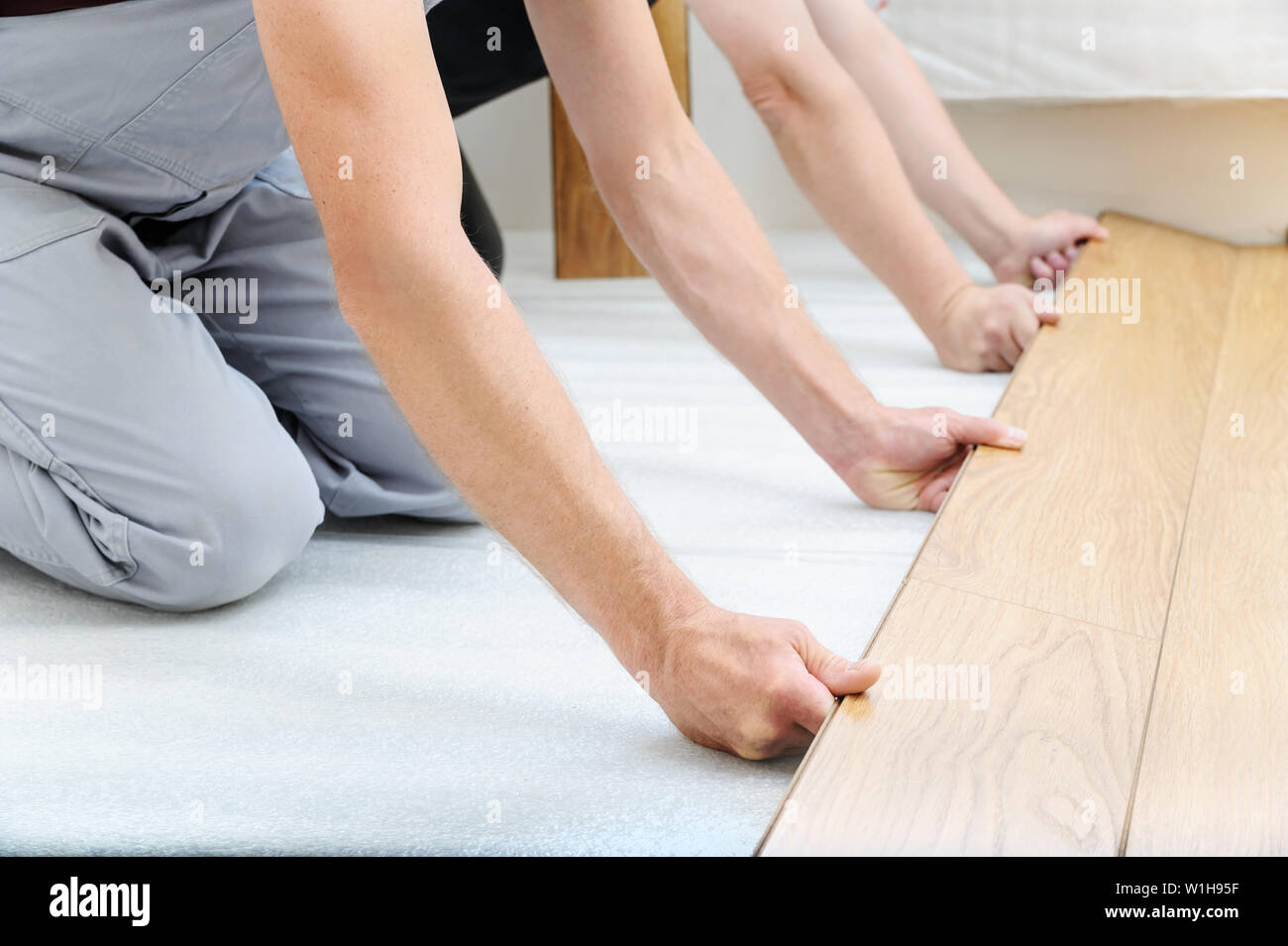 The hands of the workers are clamping the row of boards in the floor ...