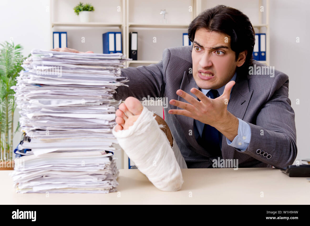 Leg injured employee working in the office Stock Photo - Alamy