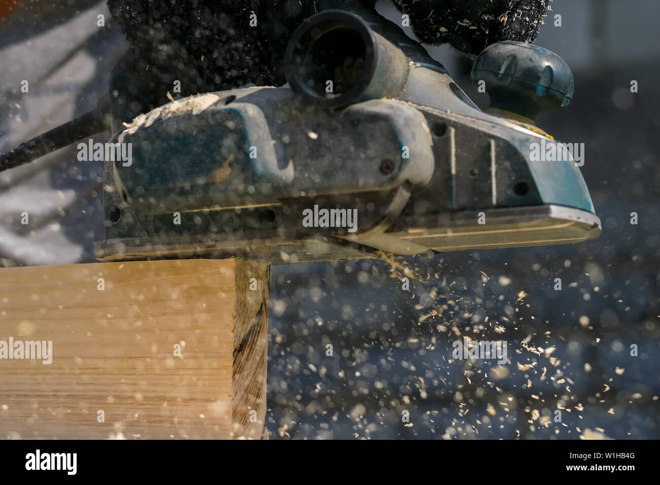 man planing boards with electric tools, chips flying in all directions ...
