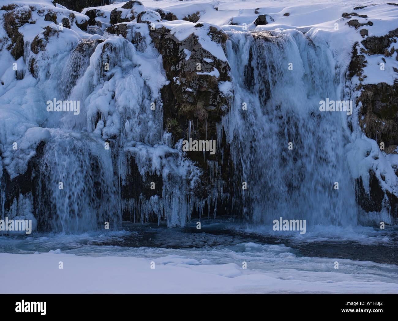 The Kirkjufellsfoss waterfall in Iceland in the early evening of winter ...