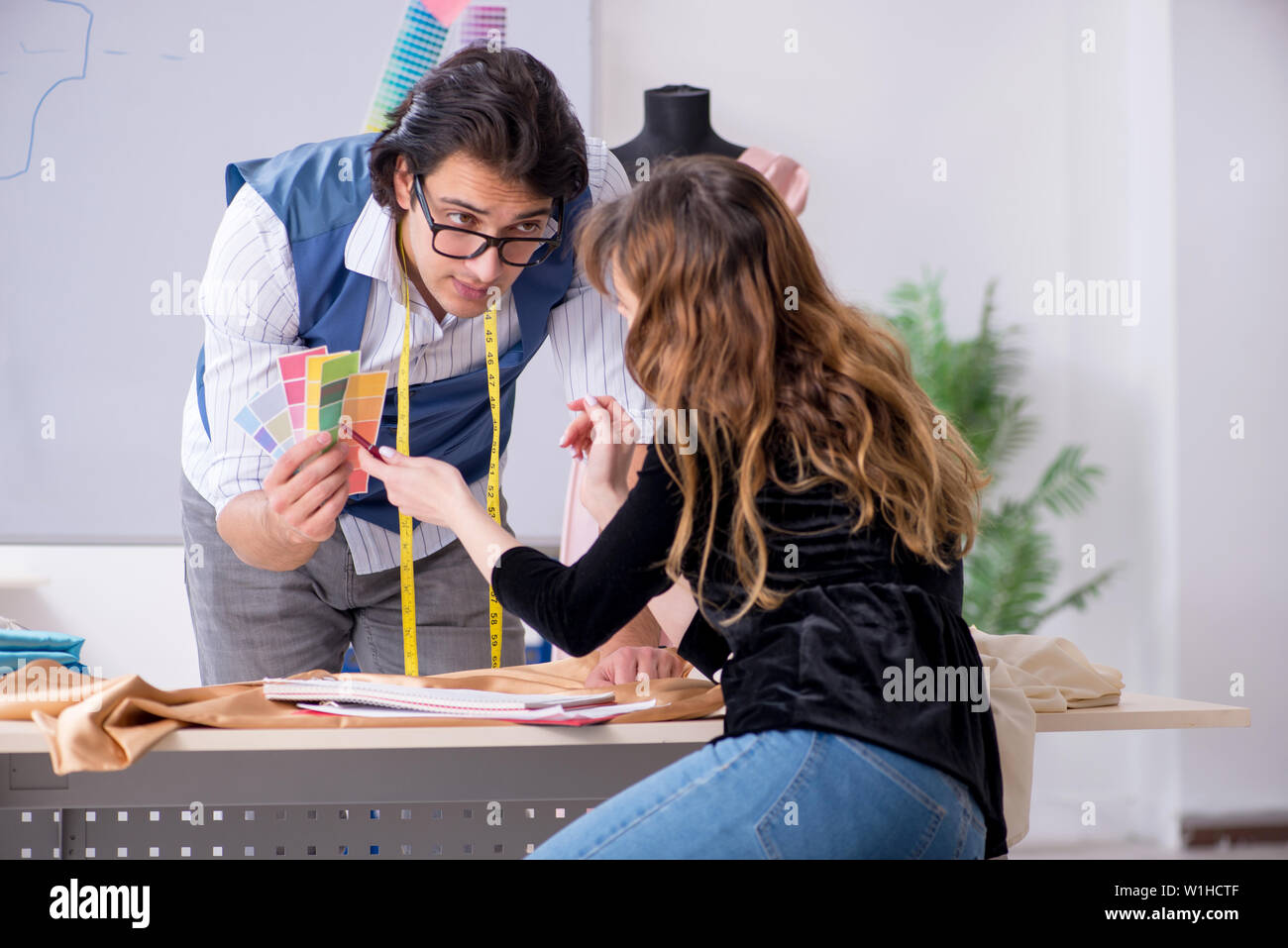 Young male tailor teaching female student Stock Photo - Alamy