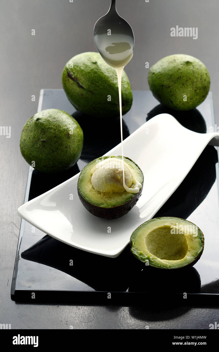 Photo of sliced fresh and ripe avocado being drizzled with sweet milk ...